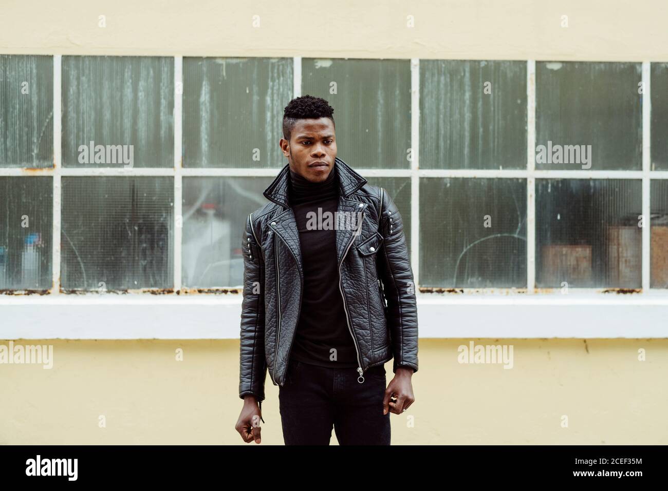 Handsome black man with close eyes standing on windows background Stock ...