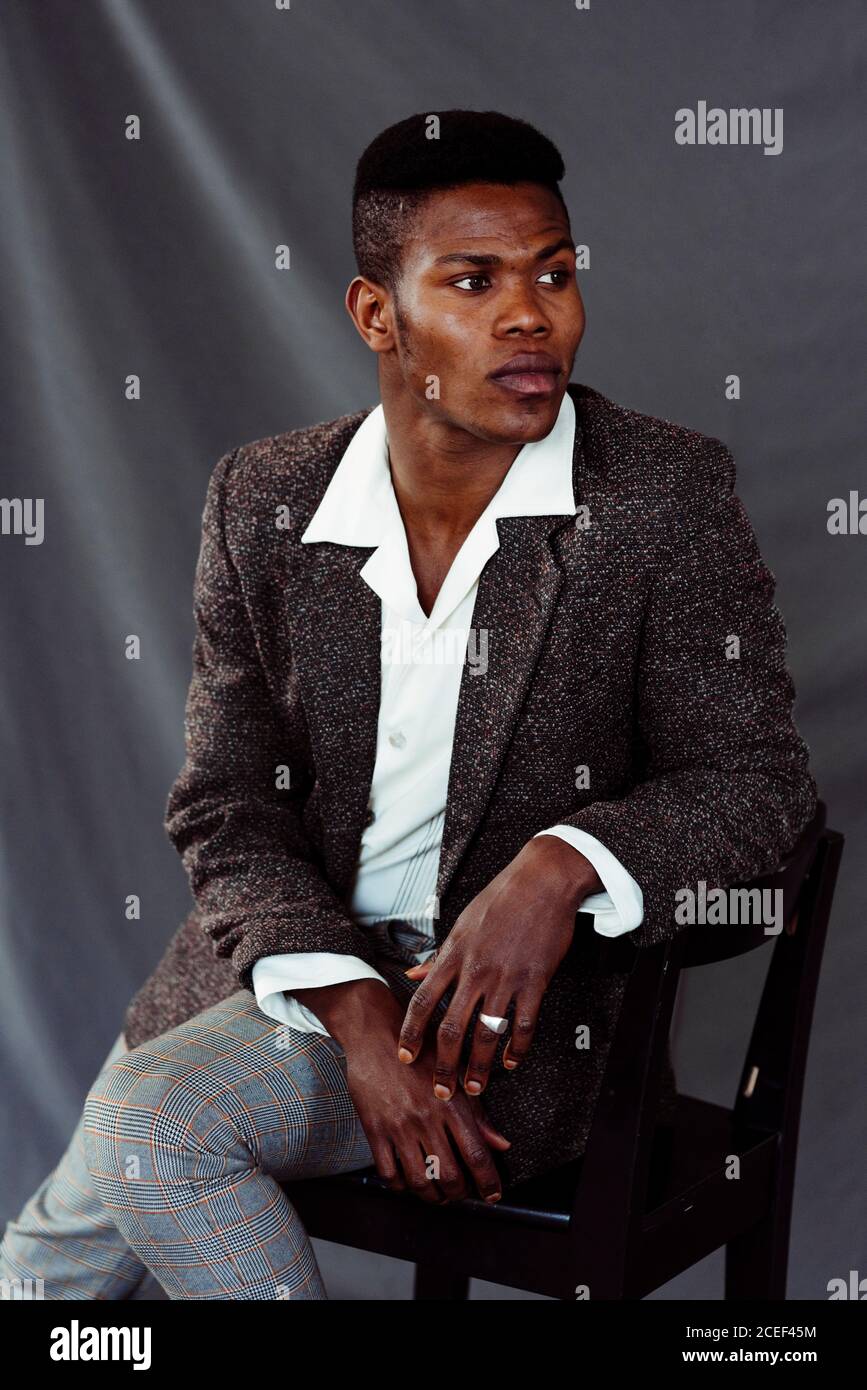 Stylish black man sitting on chair Stock Photo - Alamy