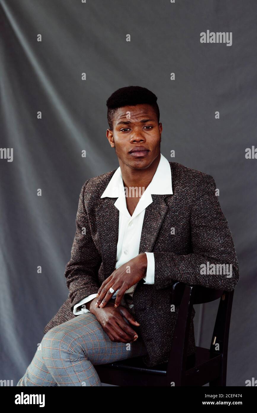 Stylish black man sitting on chair Stock Photo - Alamy