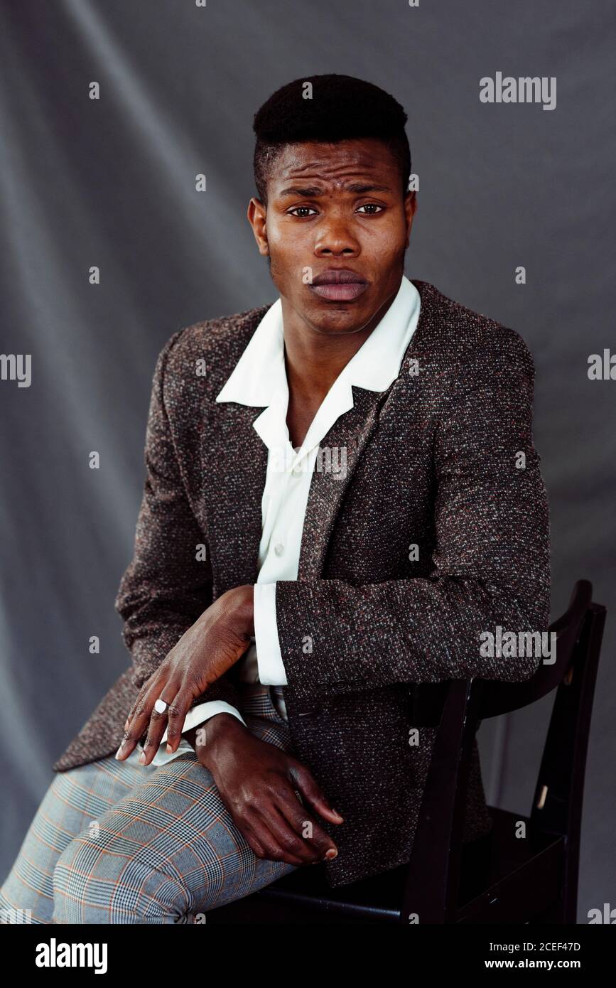 Stylish black man sitting on chair Stock Photo - Alamy