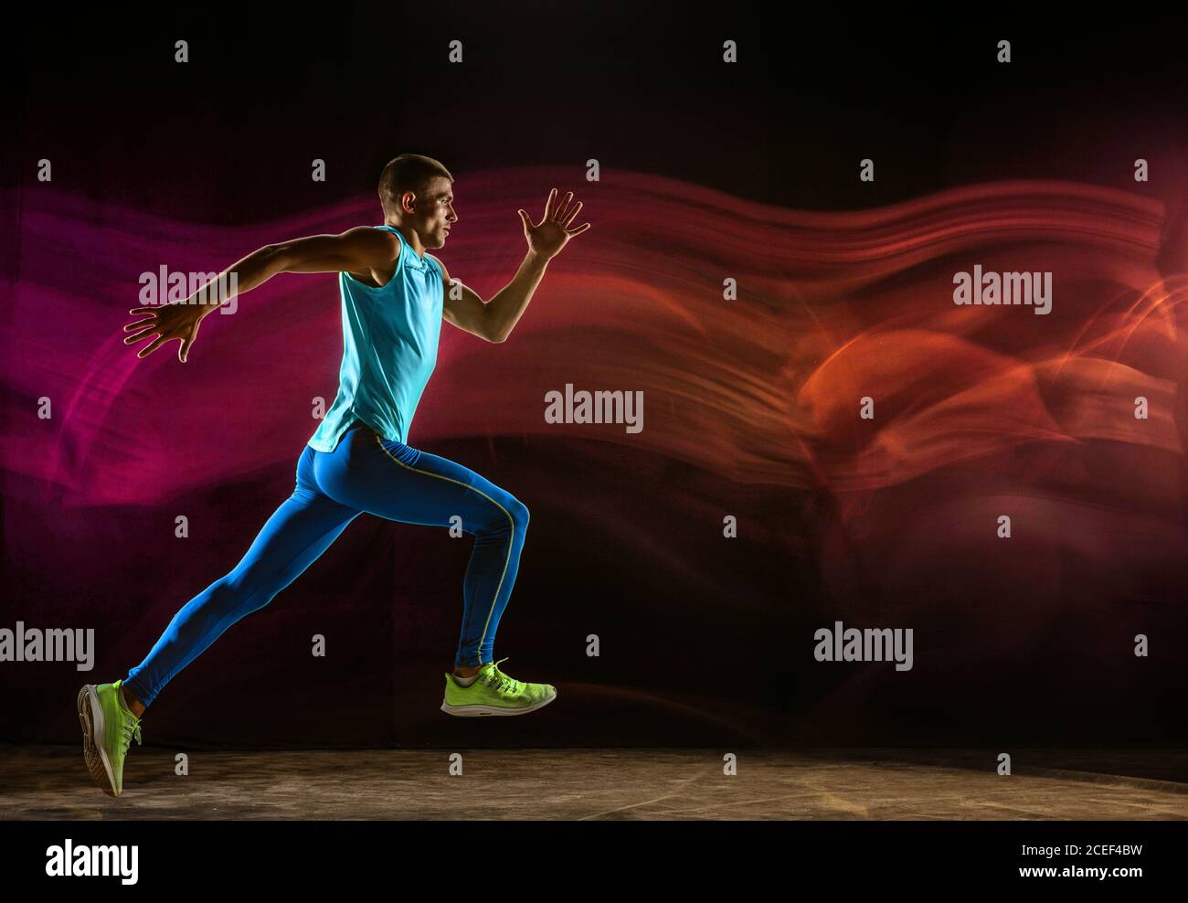 Professional male runner training isolated on black studio background ...