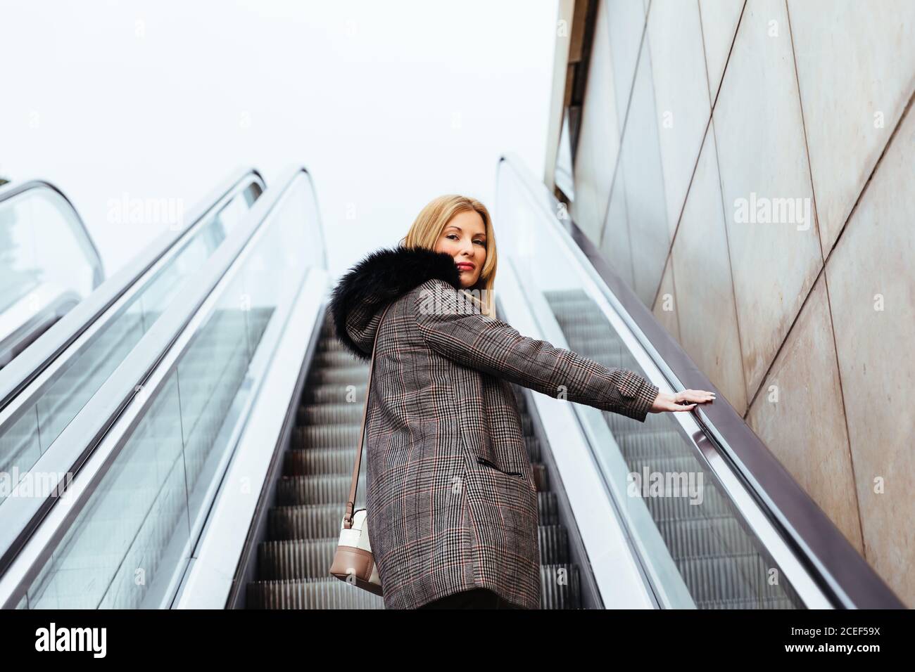 Blonde girl climbing escalators at the mall Stock Photo - Alamy