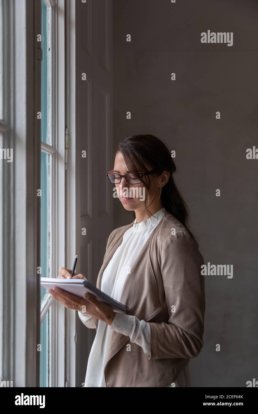 Side view of adult female in glasses talking on phone and looking out ...