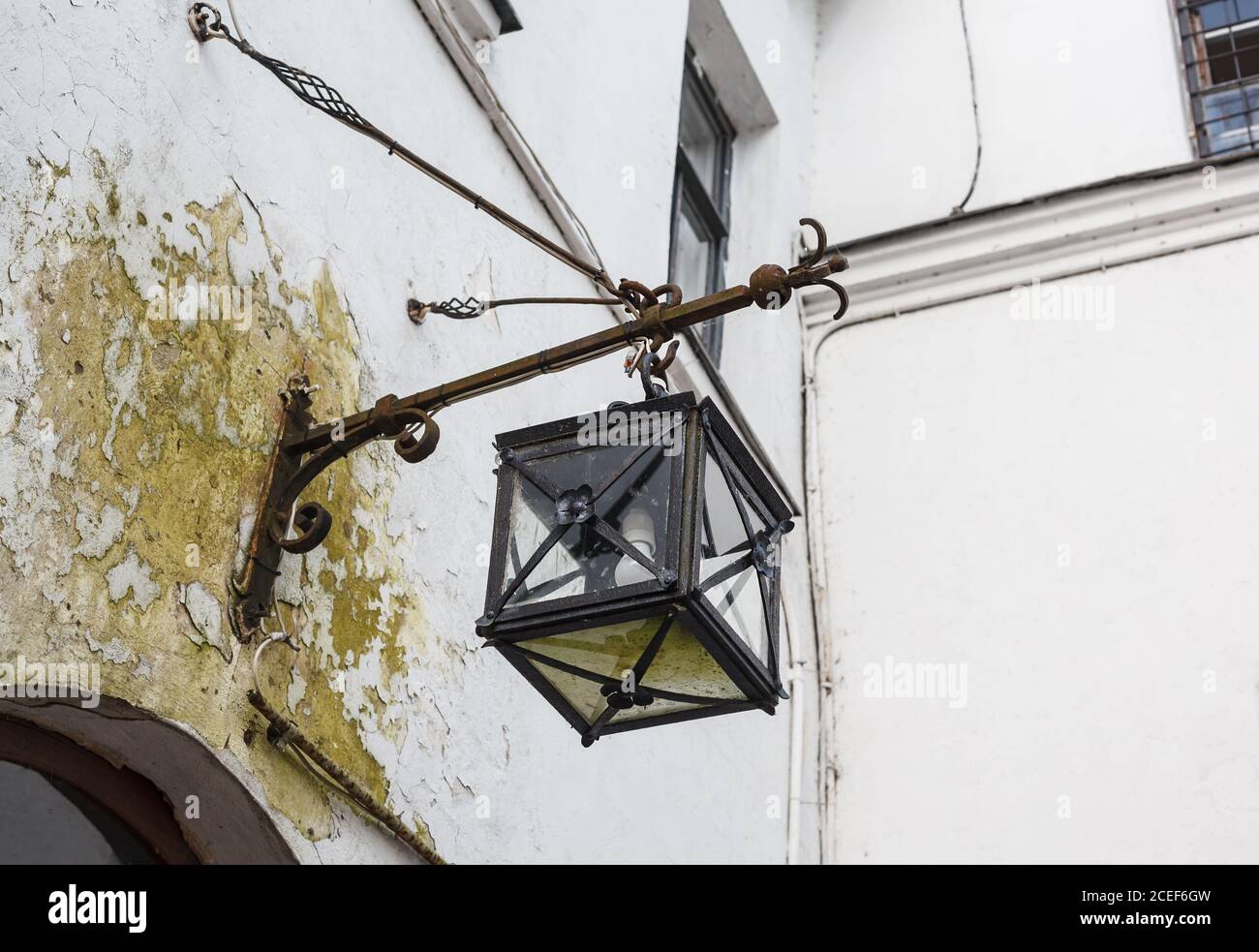 Vintage forged lamp hanging on white shabby moldy wall Stock Photo - Alamy