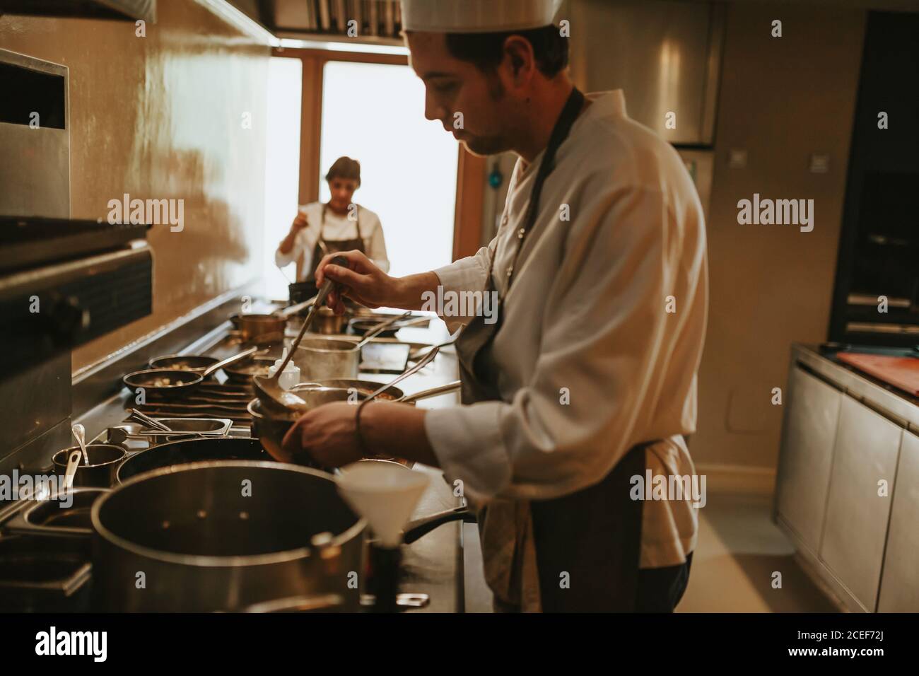 Side view of a person standing at the stove and cooking in the ...