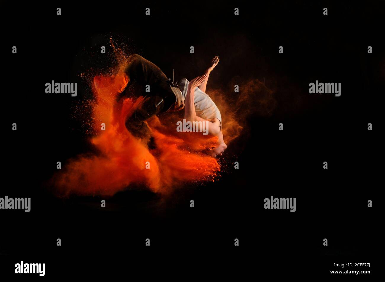 Male breakdancer does a back flip in explosion of orange powder paint ...