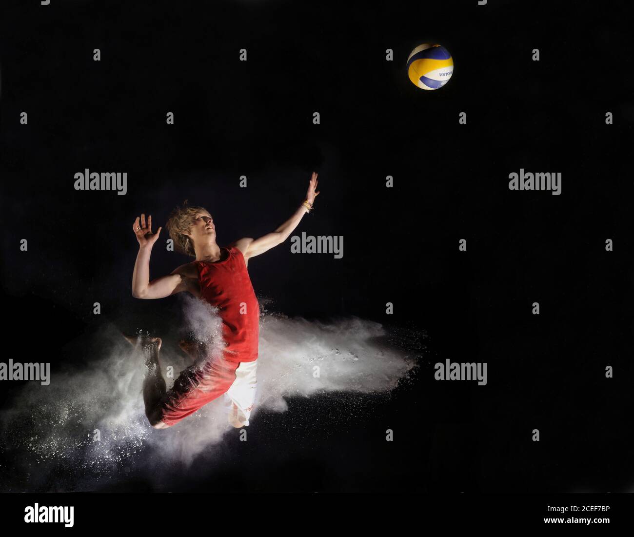 Male volleyball player jumps in midair to hit a ball whilst in an ...
