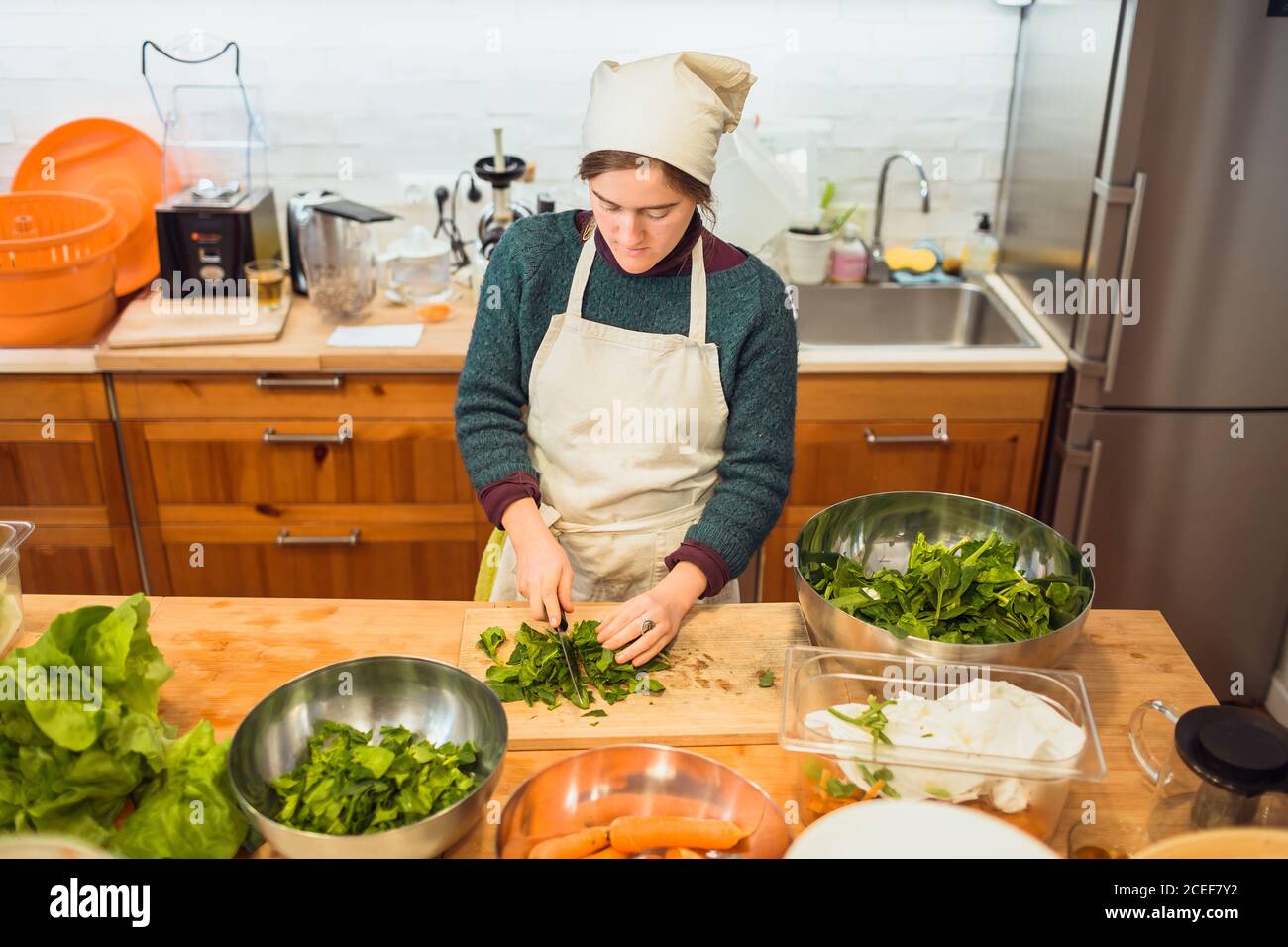 Woman cook in apron standing and chopping lettuce on kitchen of ...