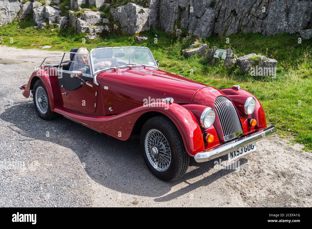 A woman behind the wheel of a 2003 Morgan 4/4 drop-head coupé sports ...