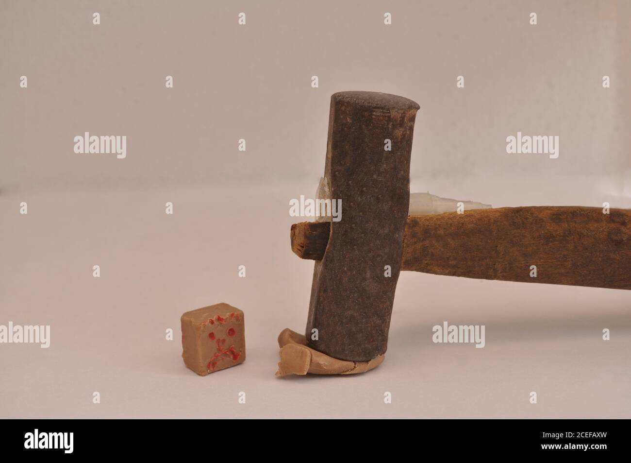 Iron hammer with wooden handle, destroying a candy in the shape of a ...