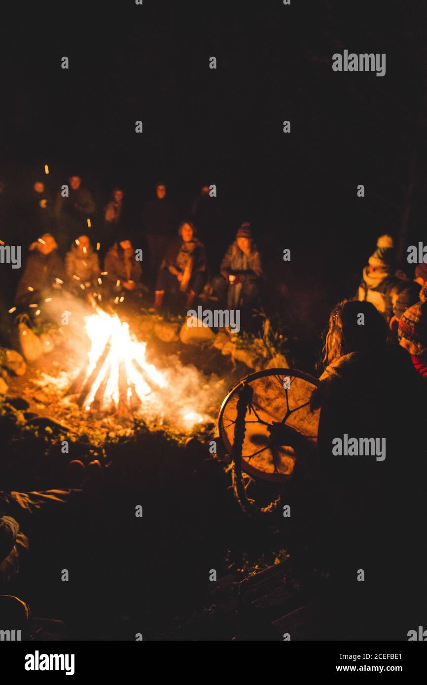 Group of people gathering around fire in woods Stock Photo - Alamy