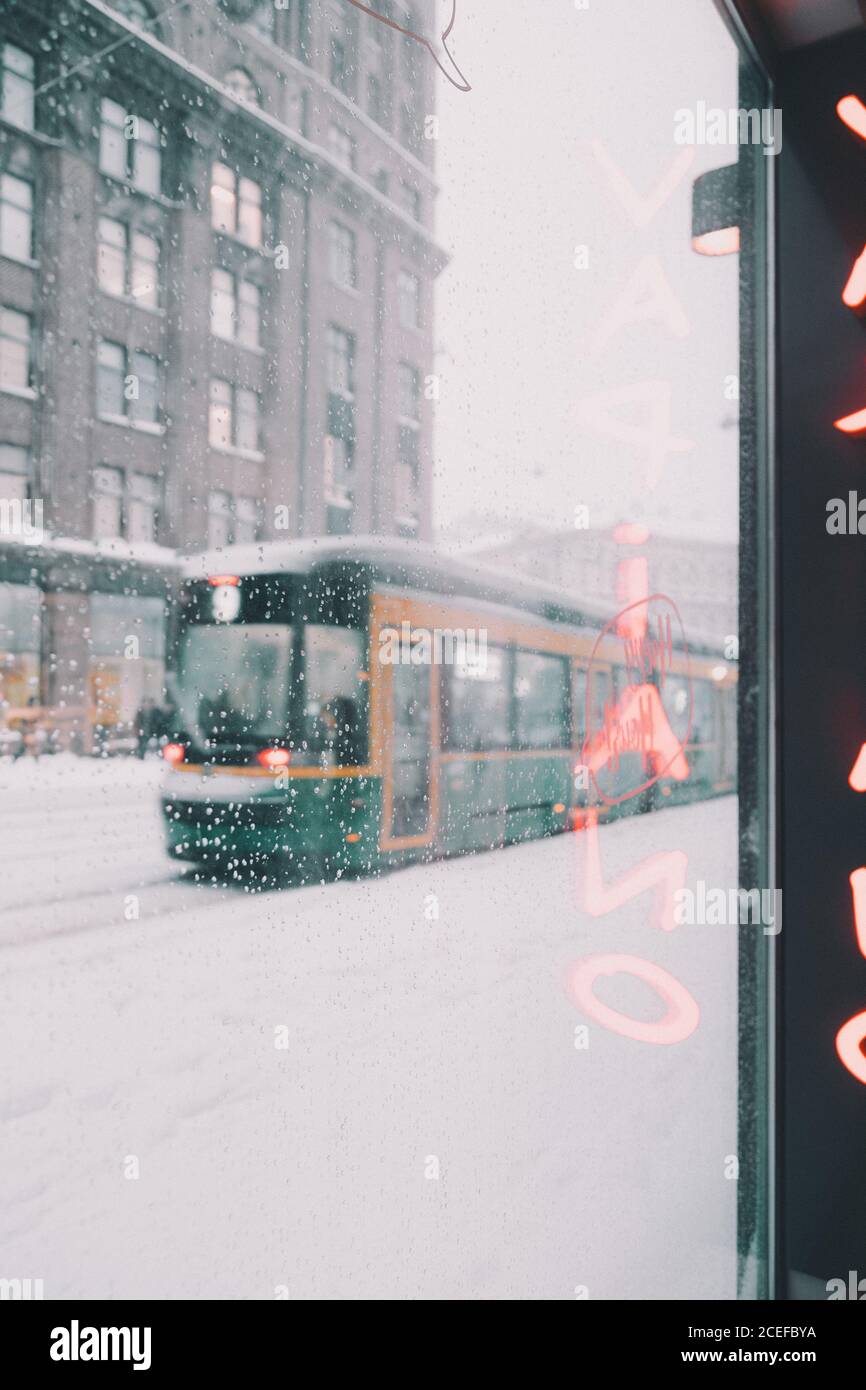 View through window of green public train on snowy railway station ...