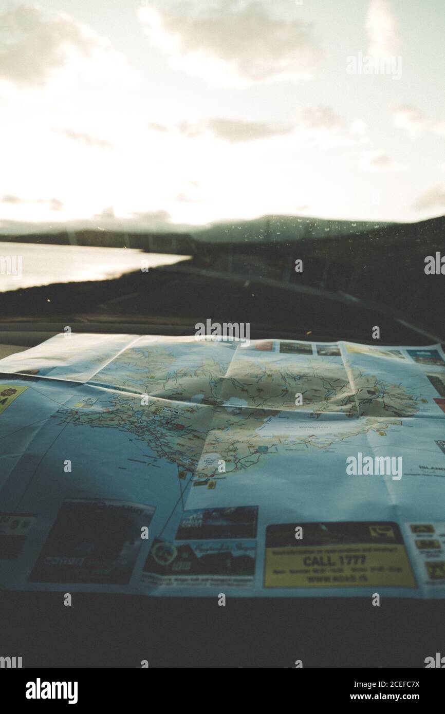 Paper map lying under windscreen of car with view of landscape behind ...
