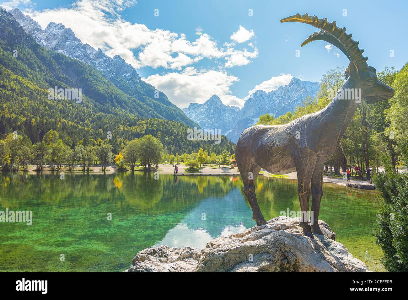 Sculpture of deer on shore of lake with azure clean water between ...