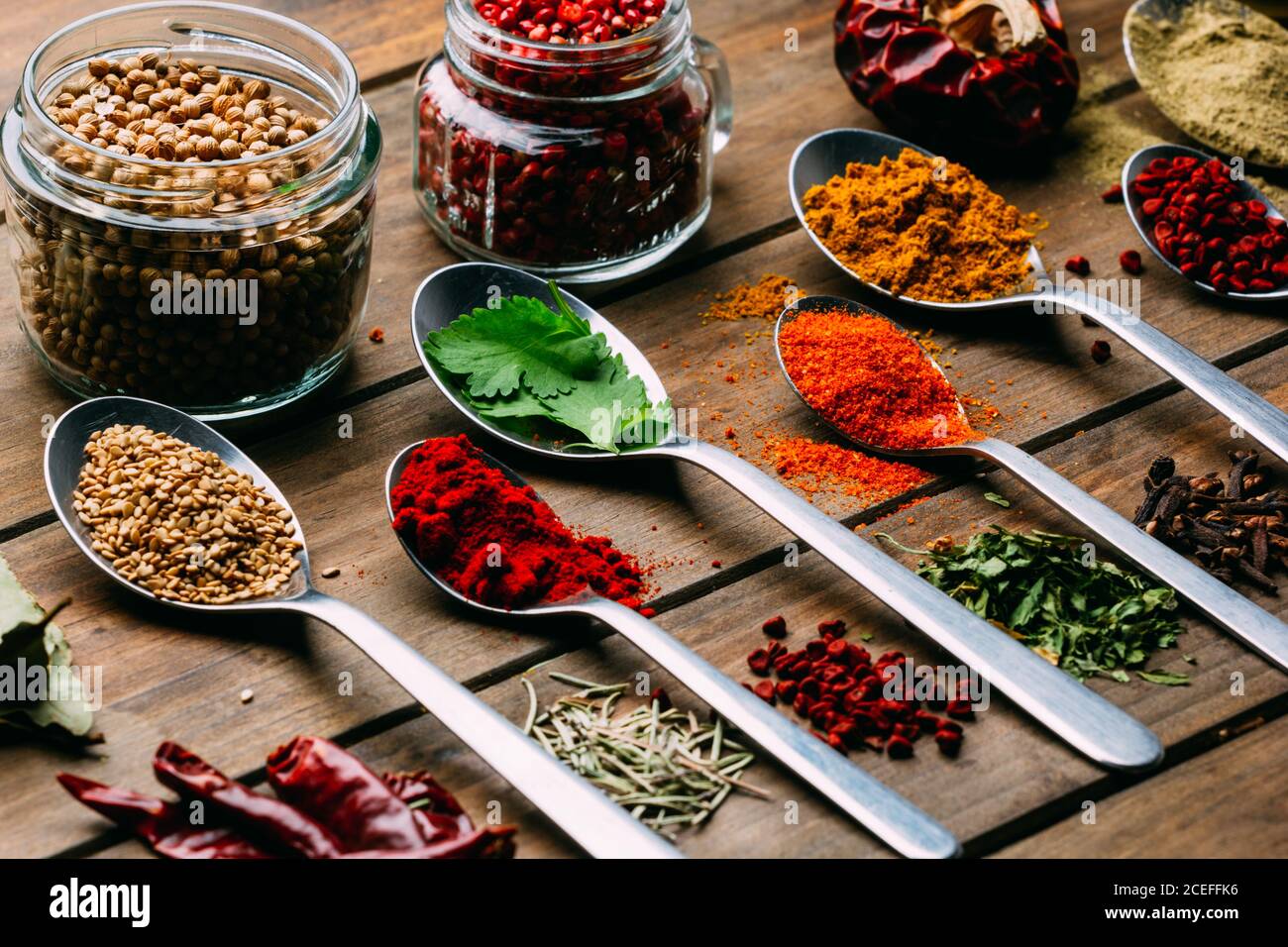 Bunch of assorted spices placed in order on lumber tabletop near bottle ...