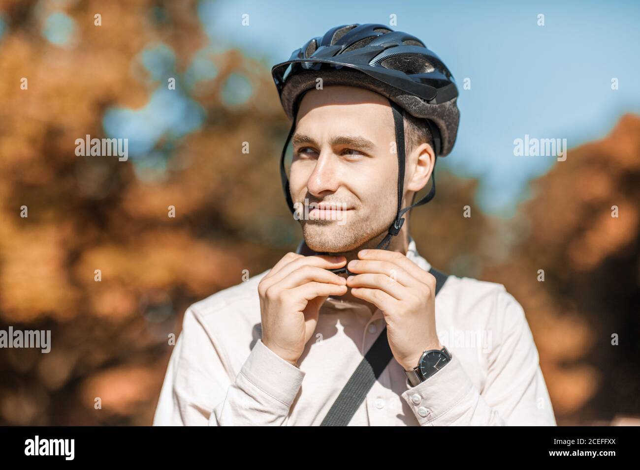 Protection while driving. Attractive young guy puts on helmet Stock ...