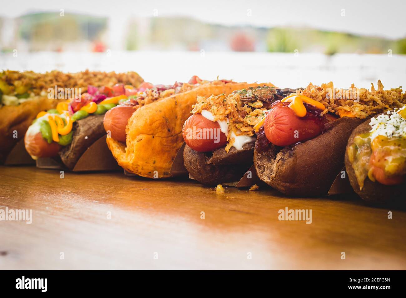 Row of assorted hot dogs with different delicious toppings and fillings ...