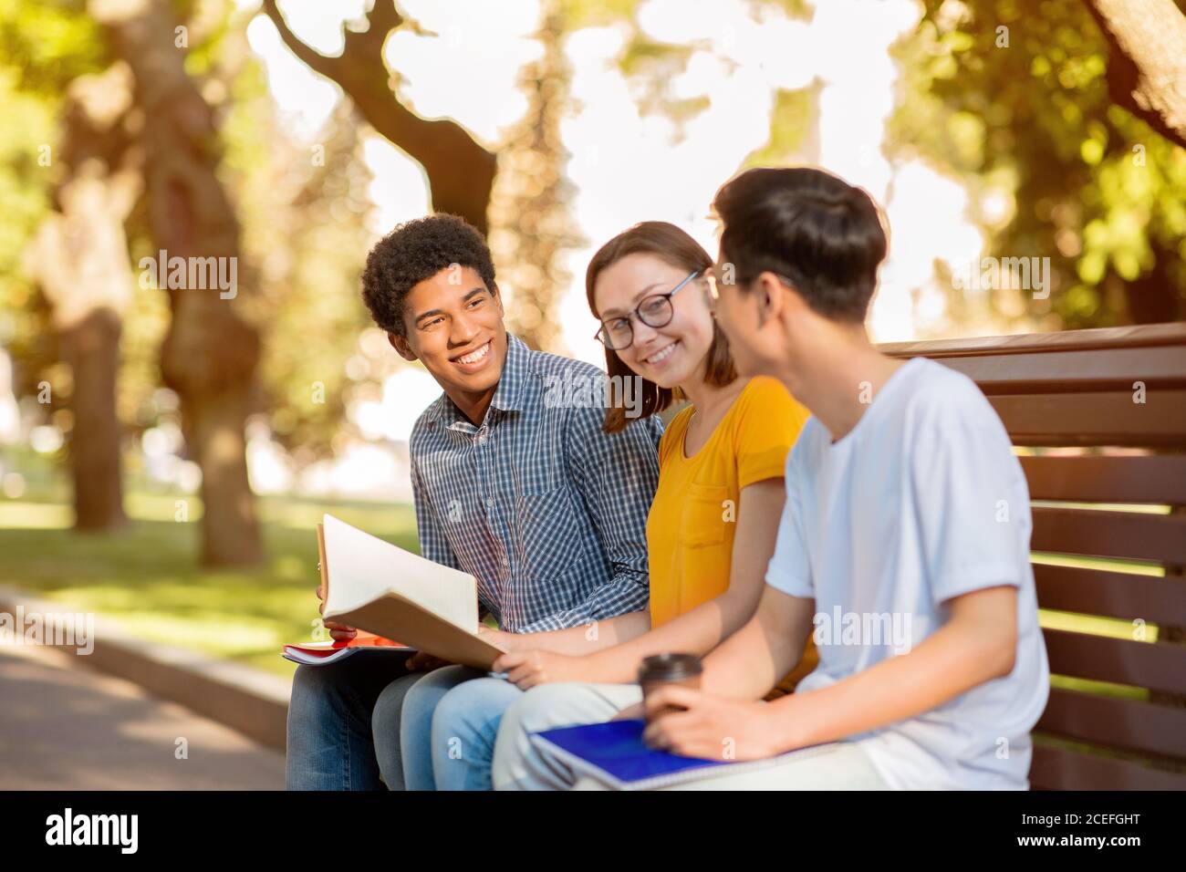Three Students Talking Discussing Classes Relaxing Sitting On Bench ...
