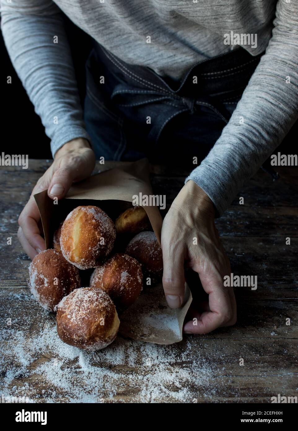 Crop human holding a set of fresh cakes with powdered sugar on wooden ...
