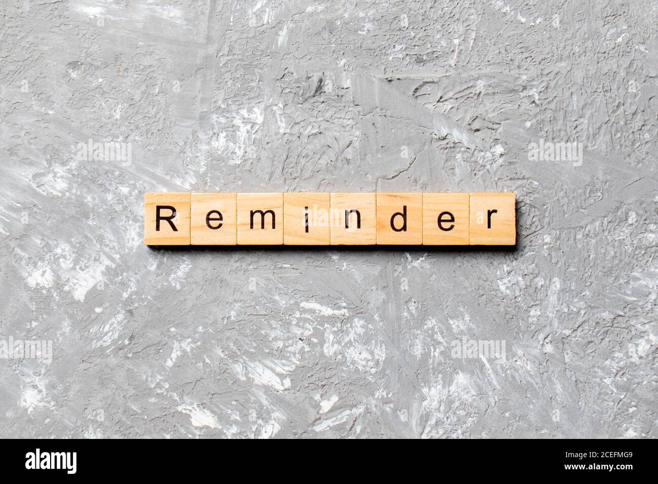 REMINDER word written on wood block. REMINDER text on cement table for ...