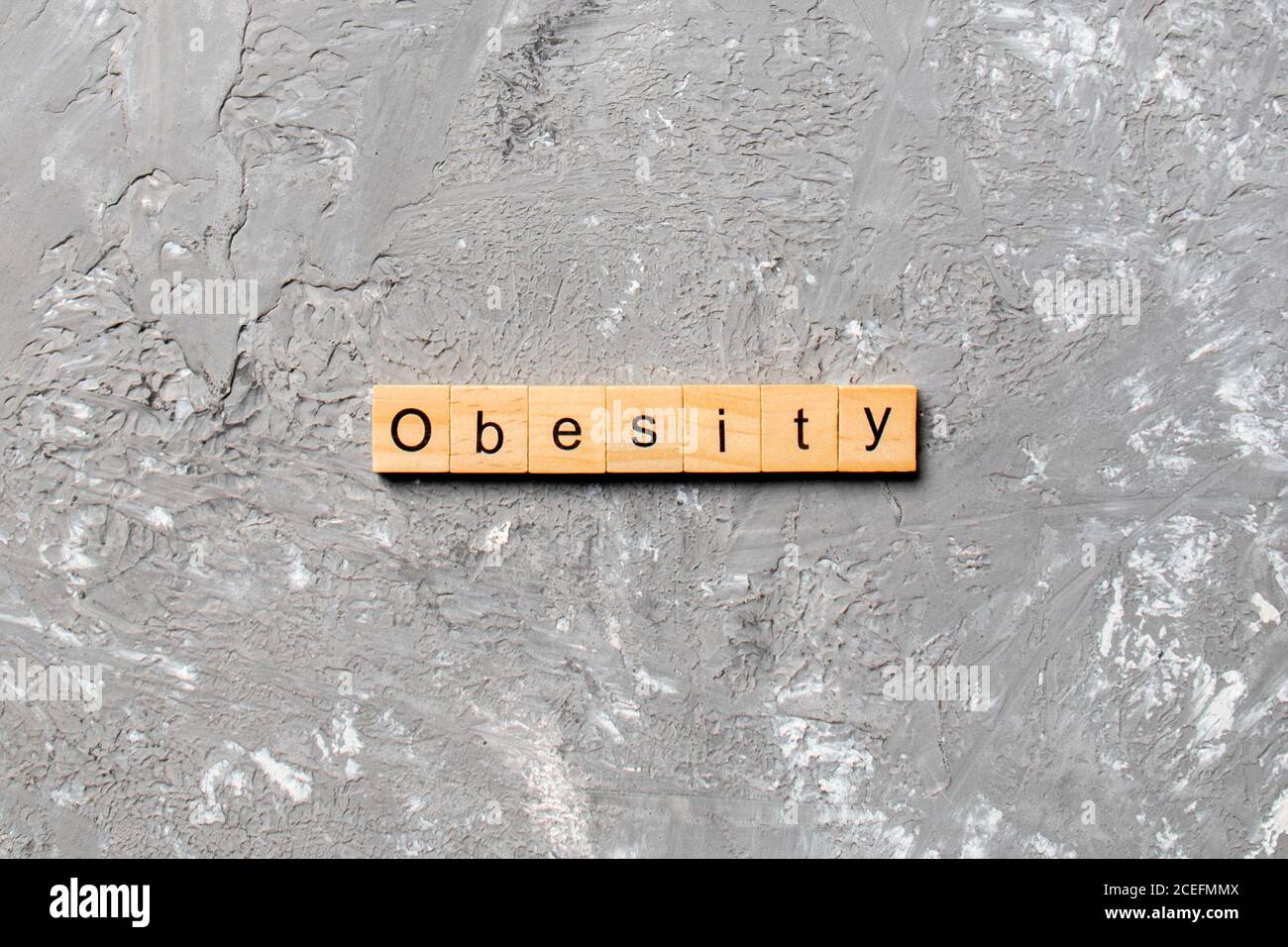 Obesity word written on wood block. Obesity text on cement table for ...