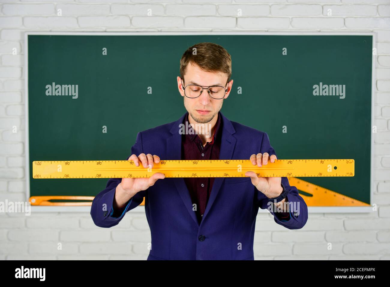 Teacher man at chalkboard holding ruler, math subject concept Stock ...