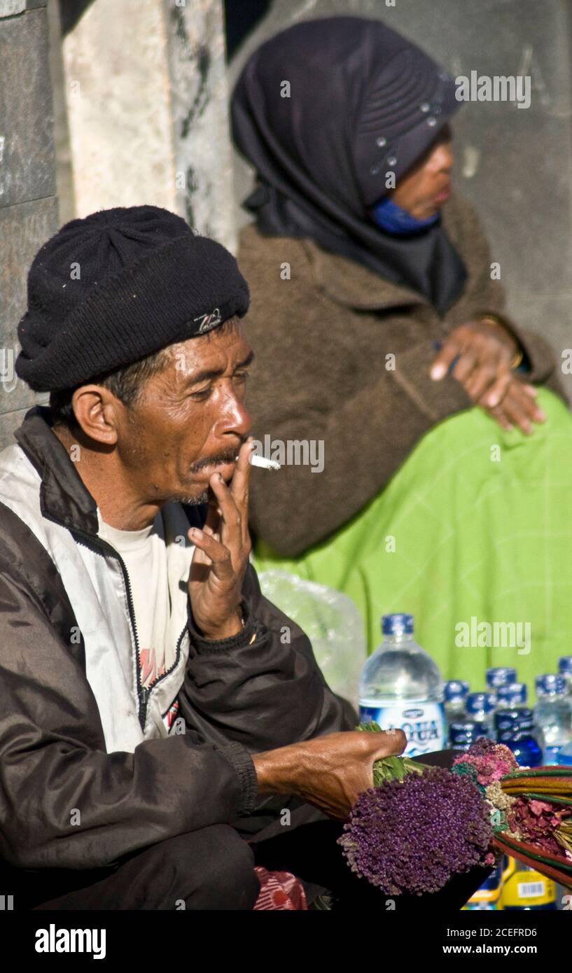 Indonesia - June 9, 2009: Side view of old poor male sitting, smoking ...