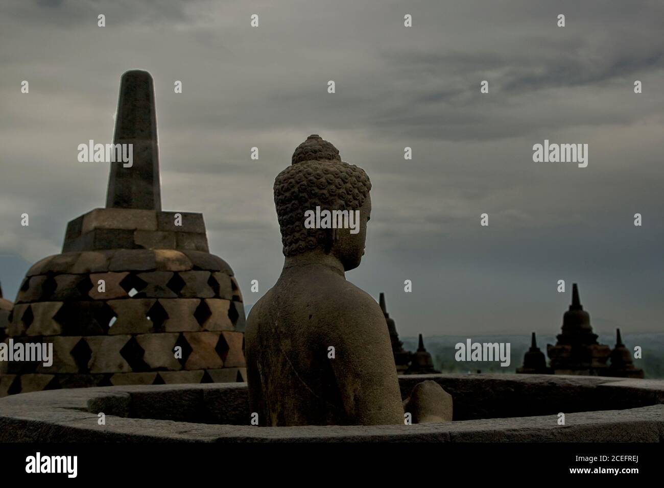 Back view of stone statue of Buddha near other constructions looking at ...