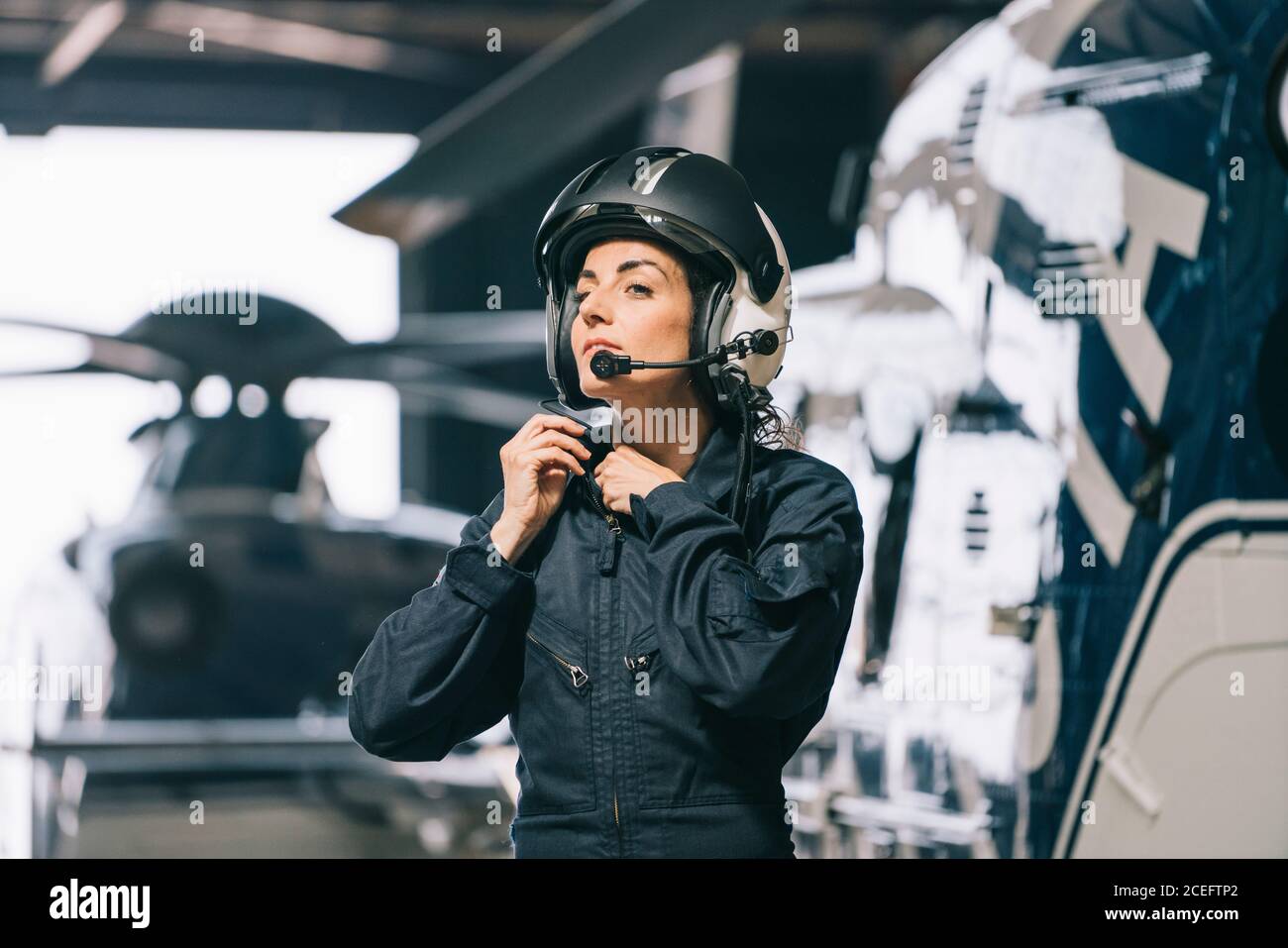 Pilot girl poses with her helicopter and helmet Stock Photo - Alamy