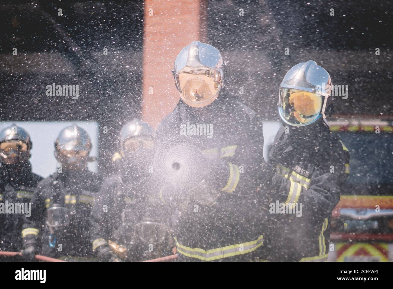 Working firemen throw water with hose Stock Photo - Alamy