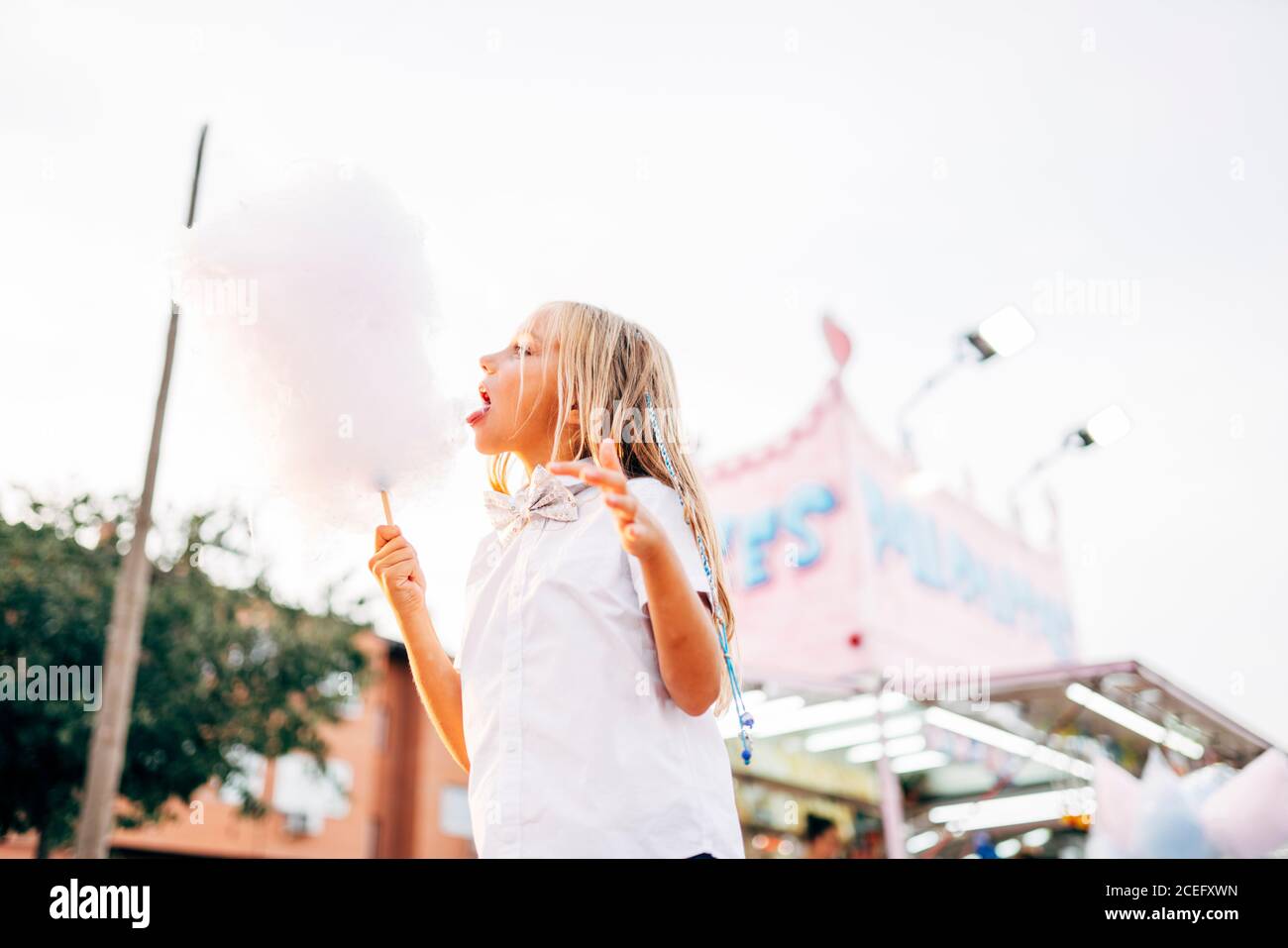Little girl has fun at the fair with lights and eats sweet cotton Stock ...