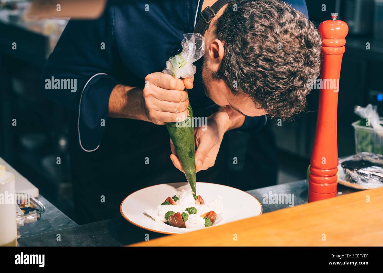 unrecognizable man in chef uniform using cooking bag to decorate ...