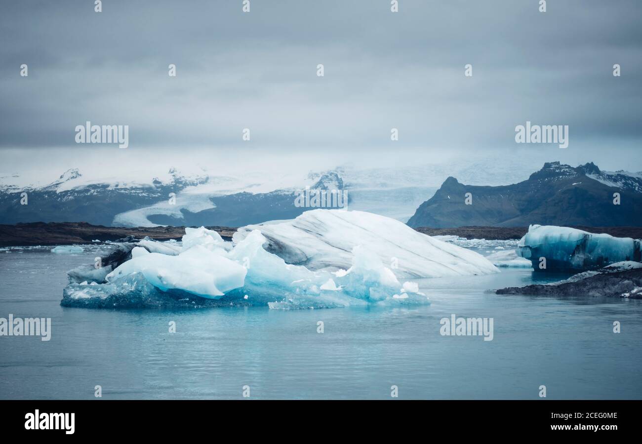 Landscape of cold sea water with white iceberg against cloudy sky ...