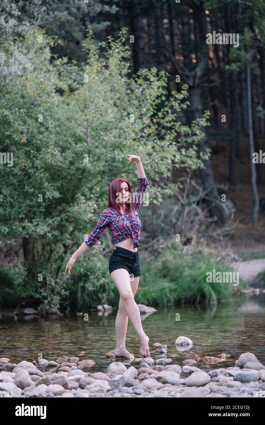 Pretty red haired girl performs exercises by the river Stock Photo - Alamy