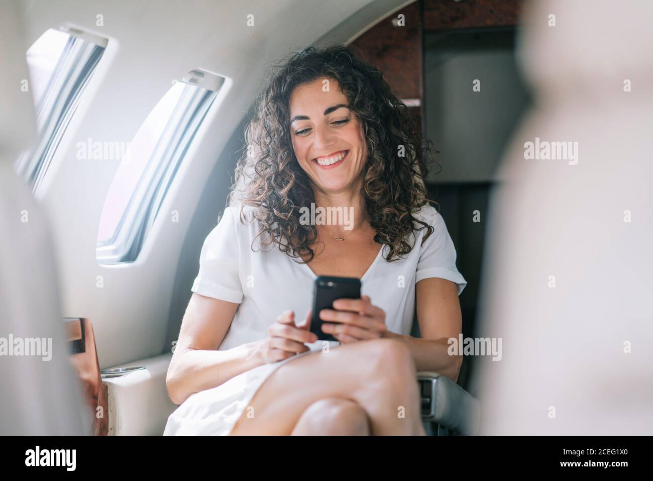 Pretty Woman works with smart phone in airplane Stock Photo - Alamy