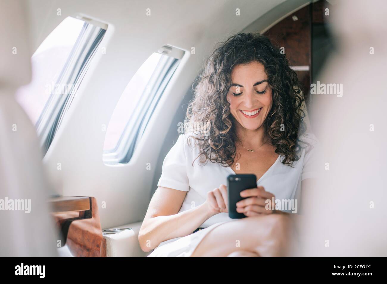Pretty Woman works with smart phone in airplane Stock Photo - Alamy