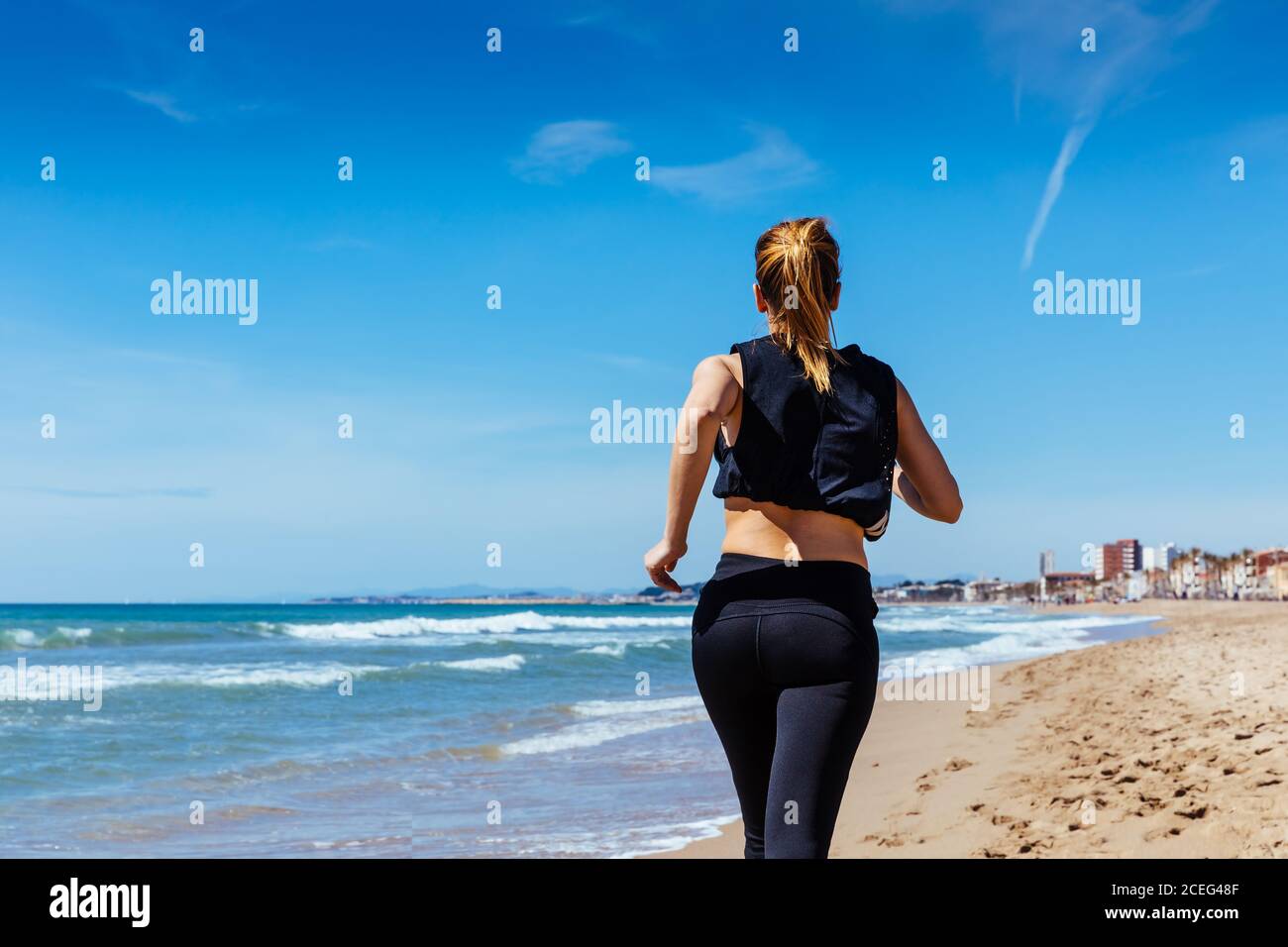 Woman running along the shore of the beach Stock Photo - Alamy