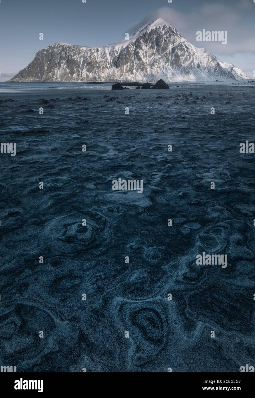 Cold water of ocean floating near distant snowy mountain in Lofoten ...