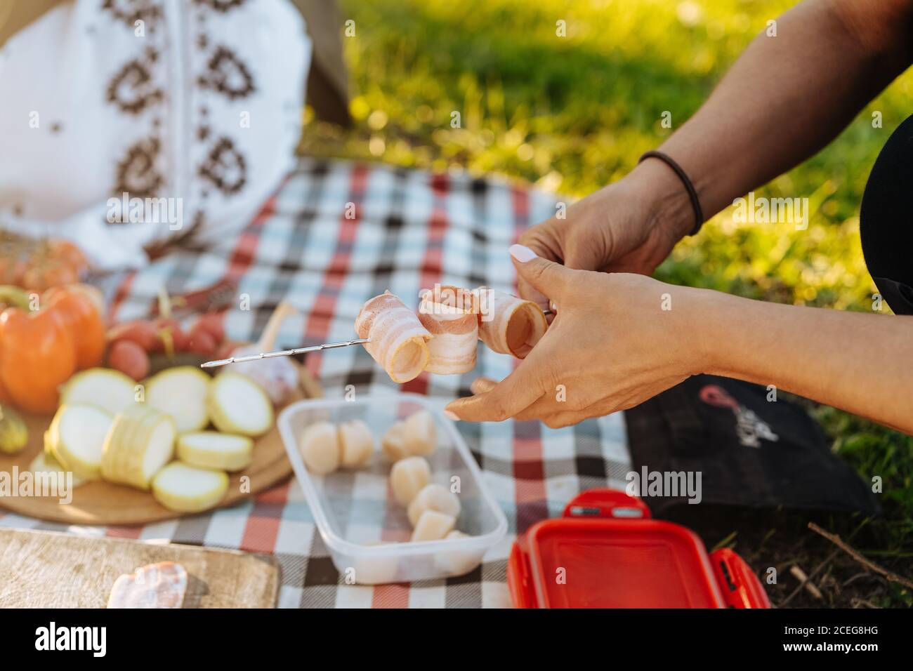 faceless shot of person arranging folded bacon strips on metal skewer ...