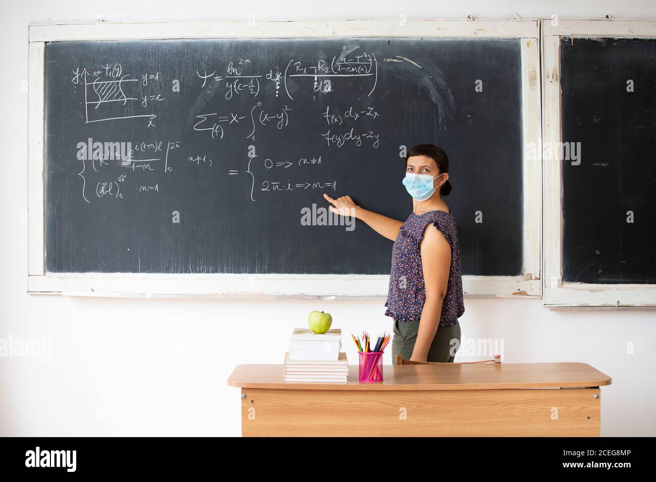 Female teacher with mask teaching math lesson at school. Social ...