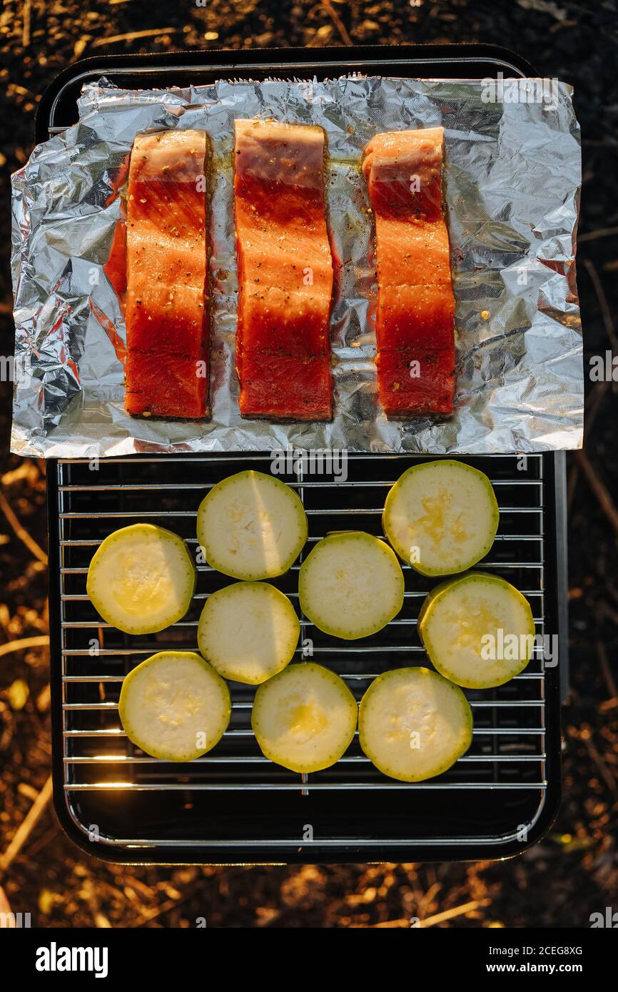 Crop shot from above of man?flipping salmon pieces with tongs on foil ...