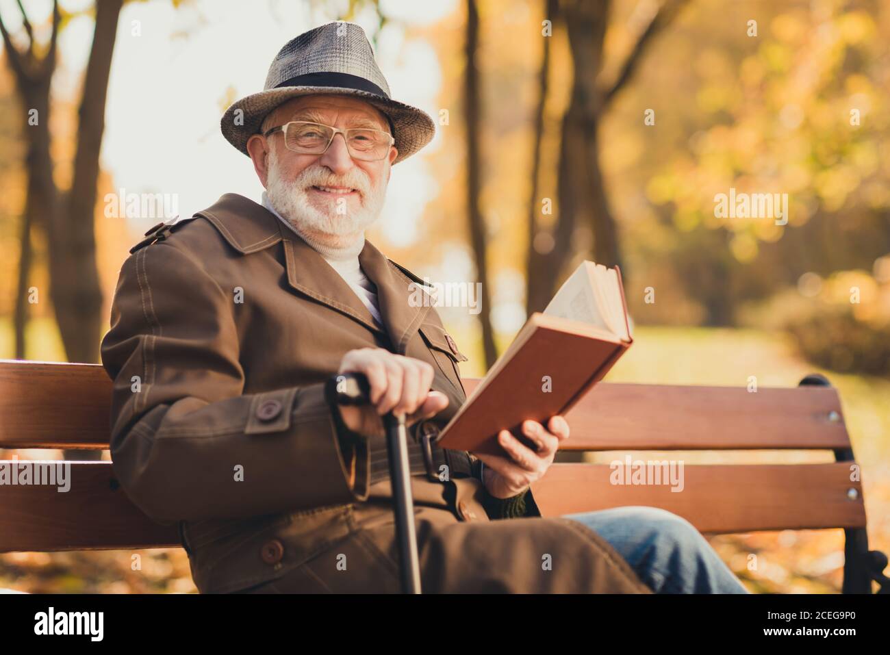 Photo of positive old man enjoy reading knowledge book story in fall ...