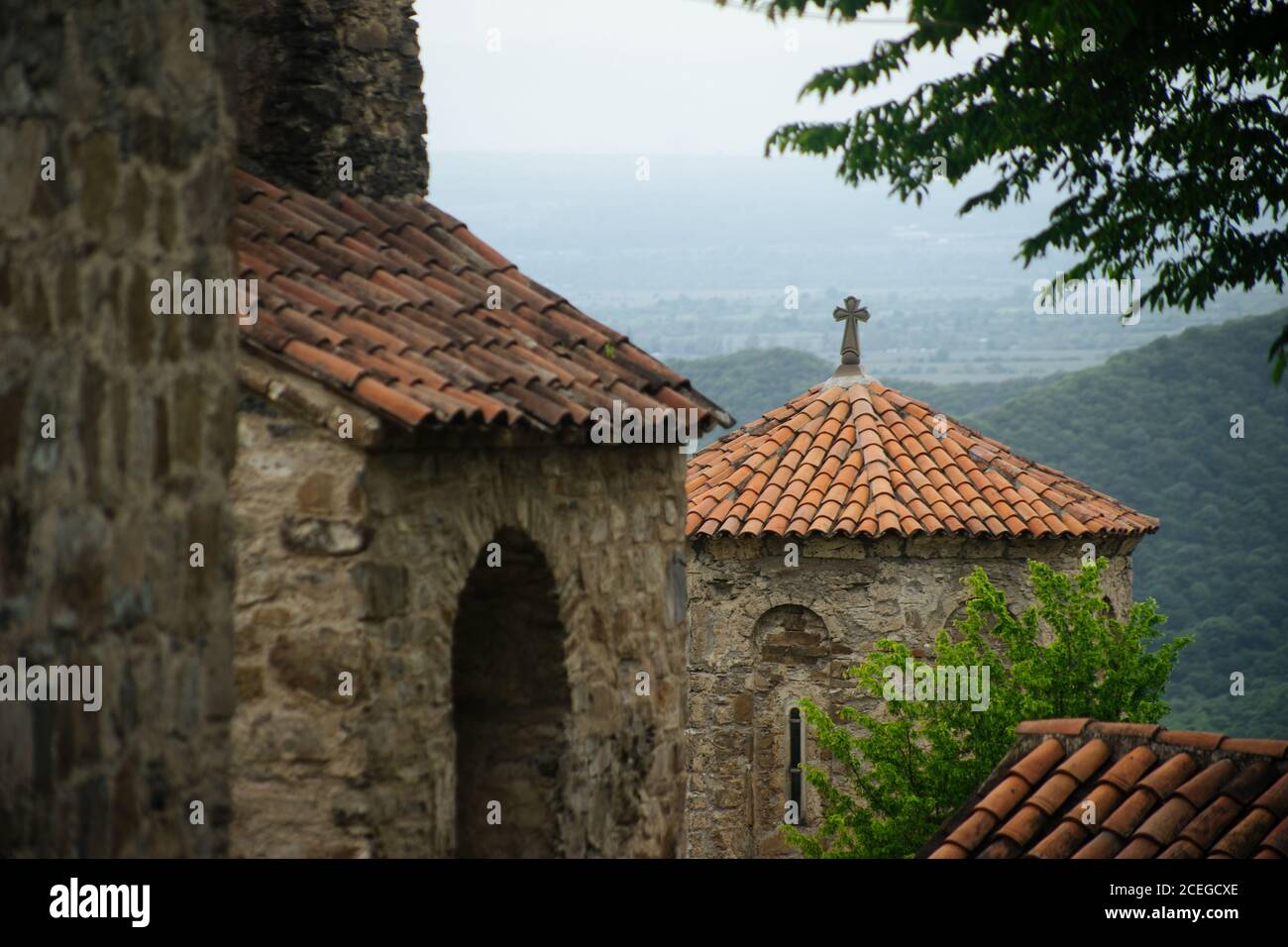 Medieval stone building with red tiled roof and Christian cross on top ...