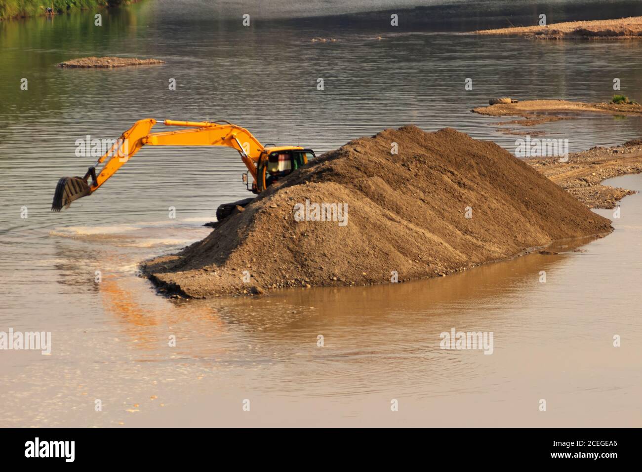 Excavator extracts sand and pebbles from a river in Southeast Asia ...