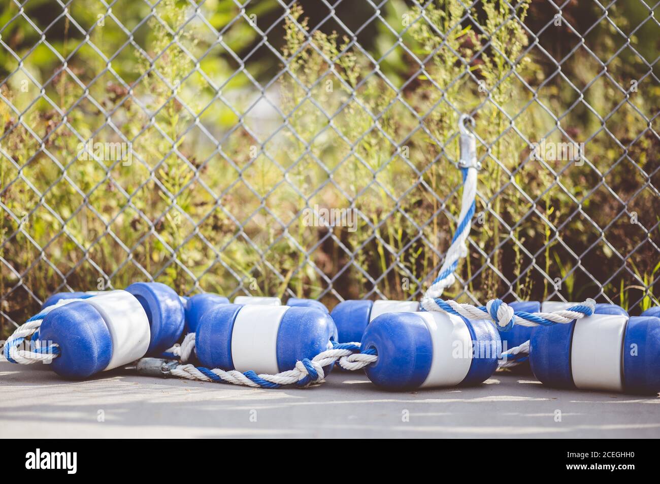 Closeup focus shot of pool lane ropes laying by the fence - concept of ...