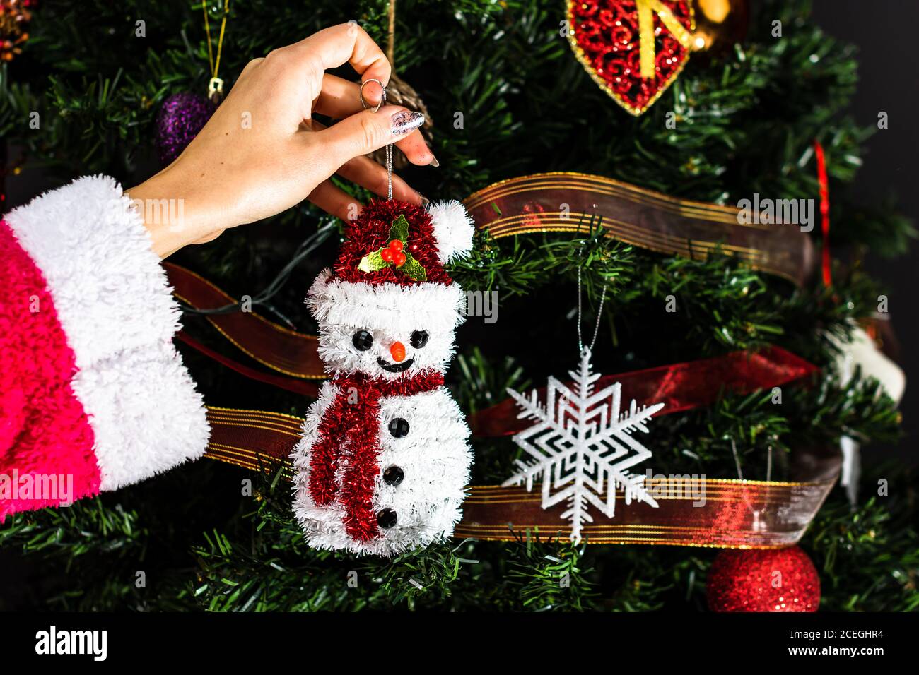 Decorating Christmas tree, hand putting Christmas decorations on fir ...