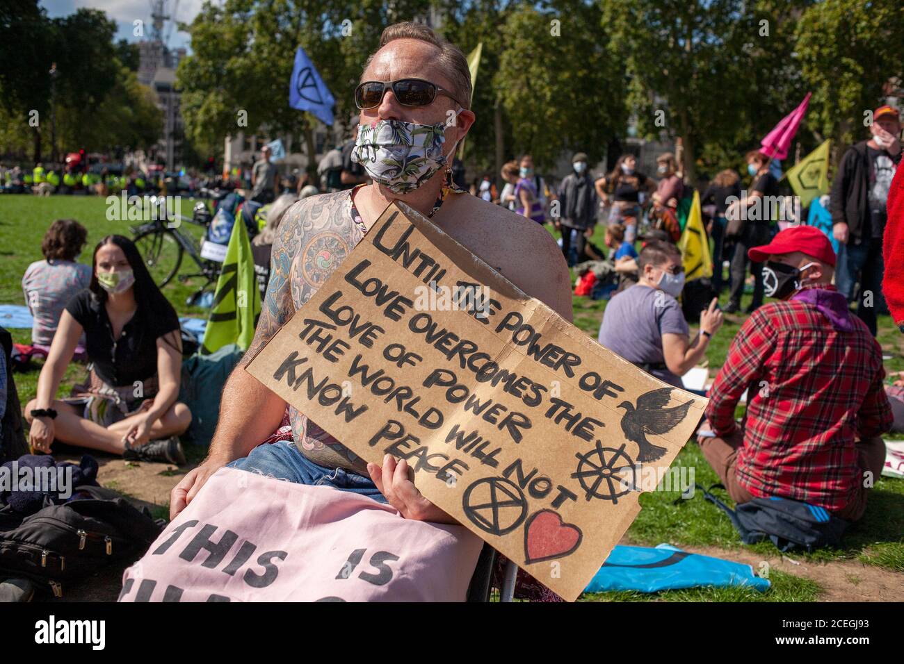 A bare chested Extinction Rebellion protester with tattoos meditates in ...