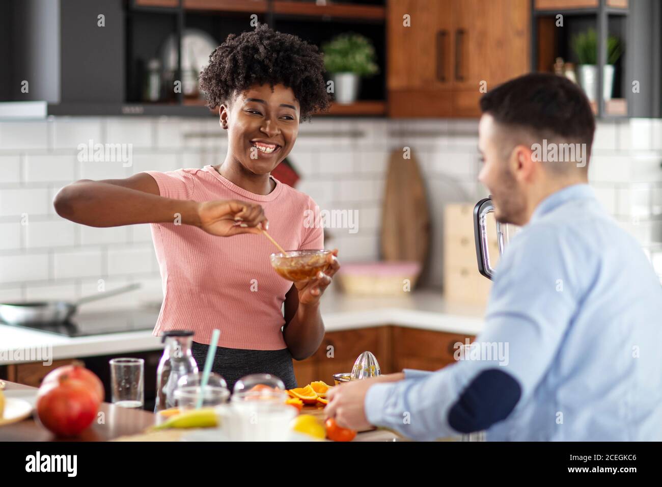 Couple in the kitchen smile and make juice Stock Photo - Alamy