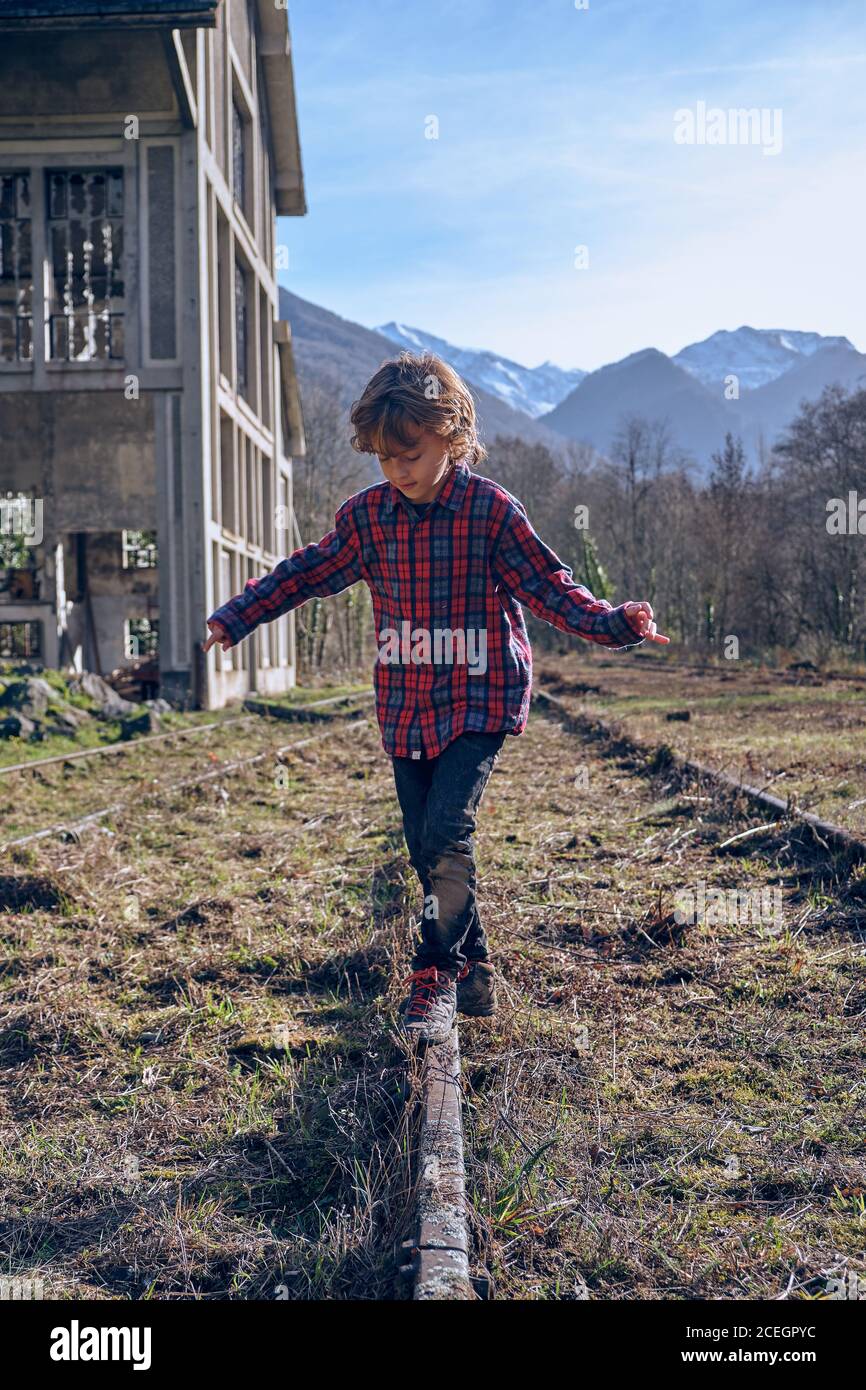 boy balancing on old railways near building and mountains Stock Photo ...
