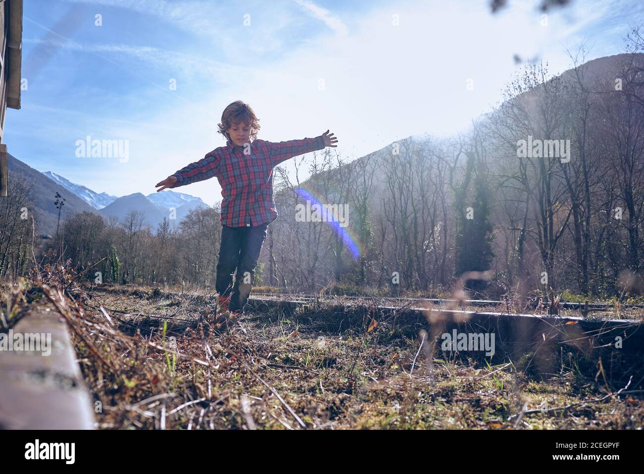 boy balancing on old railways near building and mountains Stock Photo ...